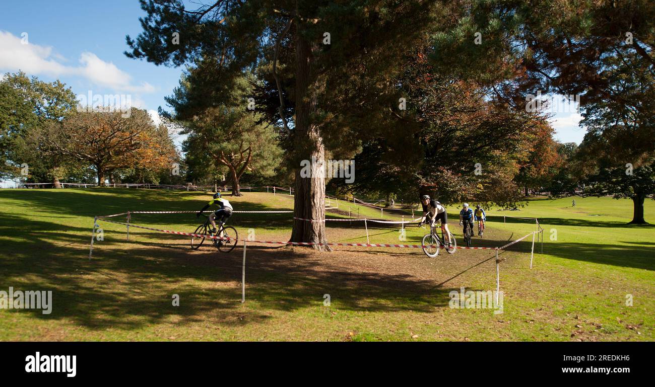 Cyclocross bike racers ride the green race course in the leafy grounds ...