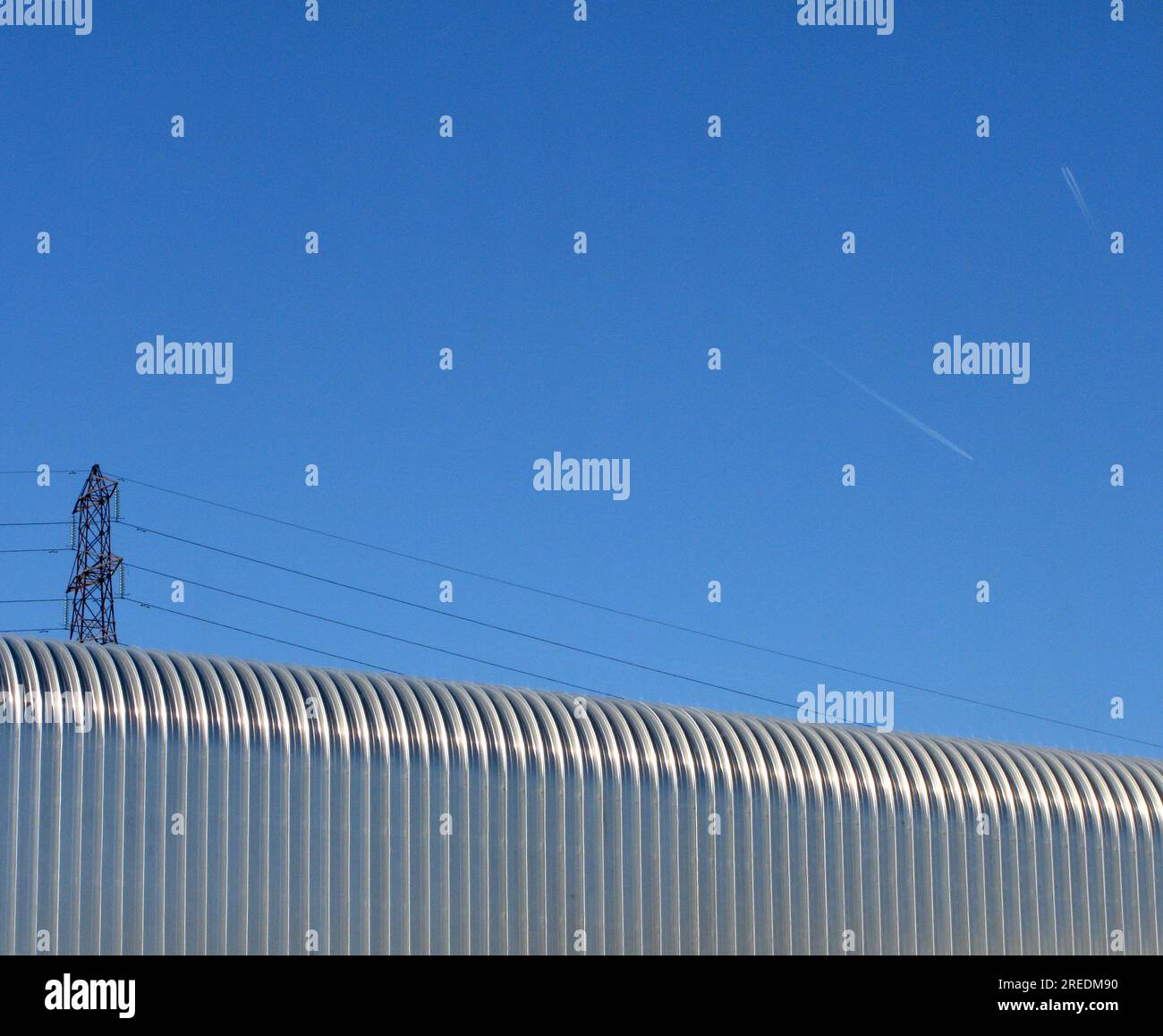 An electricity pylon pokes out from behind a metal corrugated iron roof ...