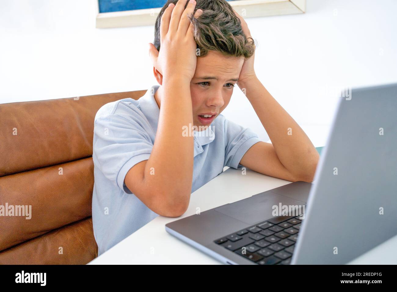 stressed teen boy studying with laptop while sitting on desk at home ...