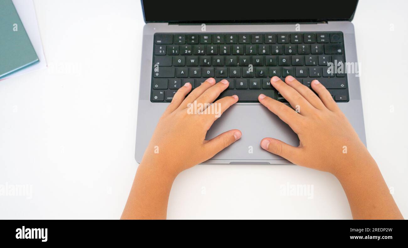 Close-up cropped shot of unrecognizable child boy typing on laptop ...