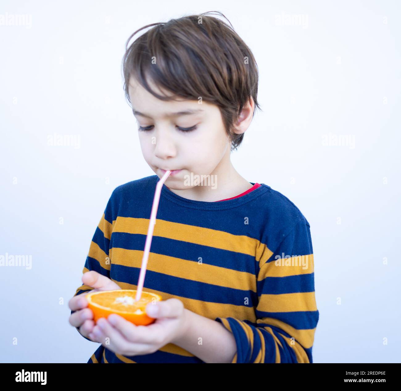 Little cute boy taking juice out of orange Stock Photo - Alamy