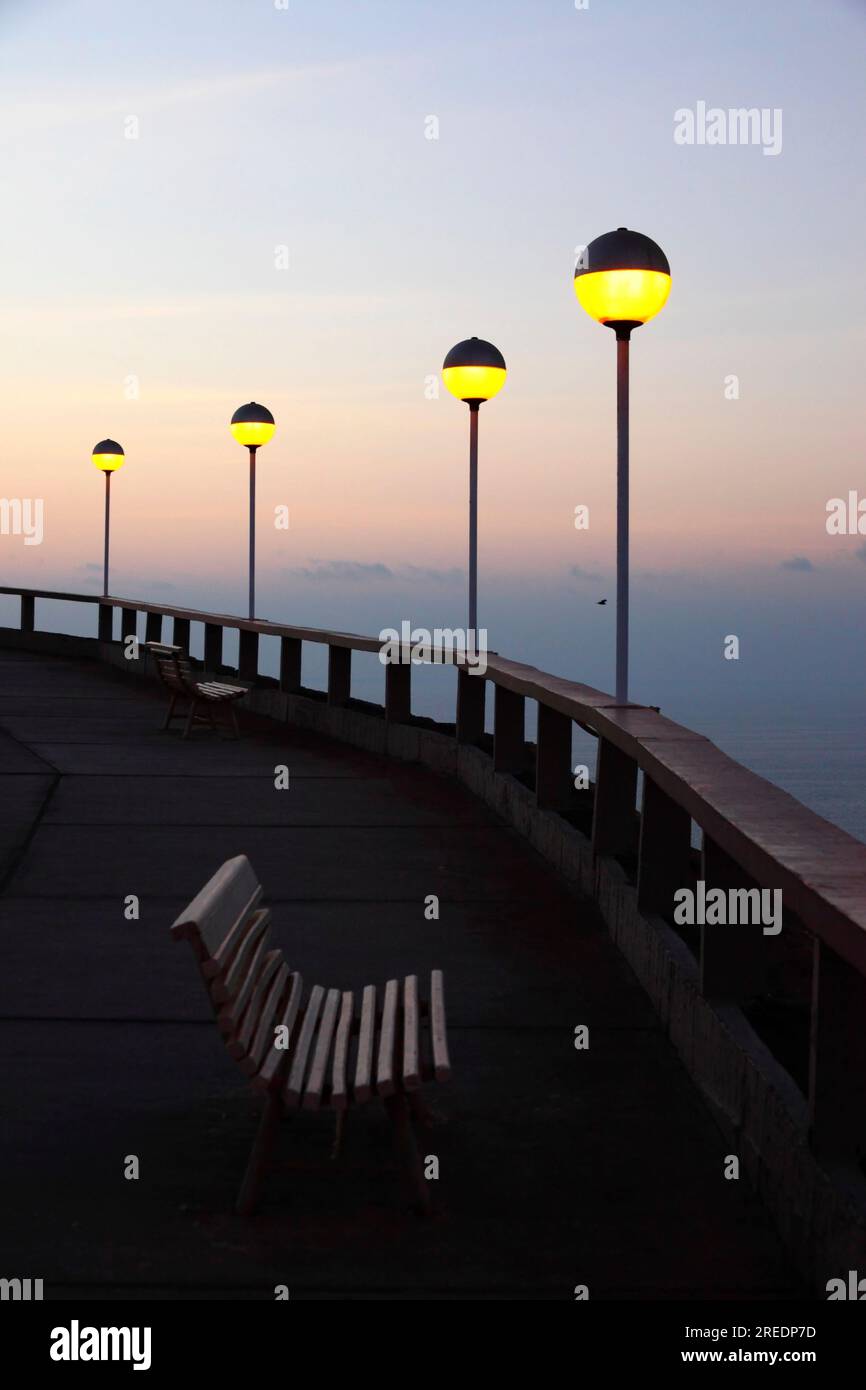 Empty white wooden seat and spherical yellow street lamps on El Morro ...