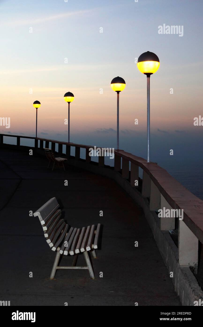 Empty white wooden seat and spherical yellow street lamps on El Morro ...