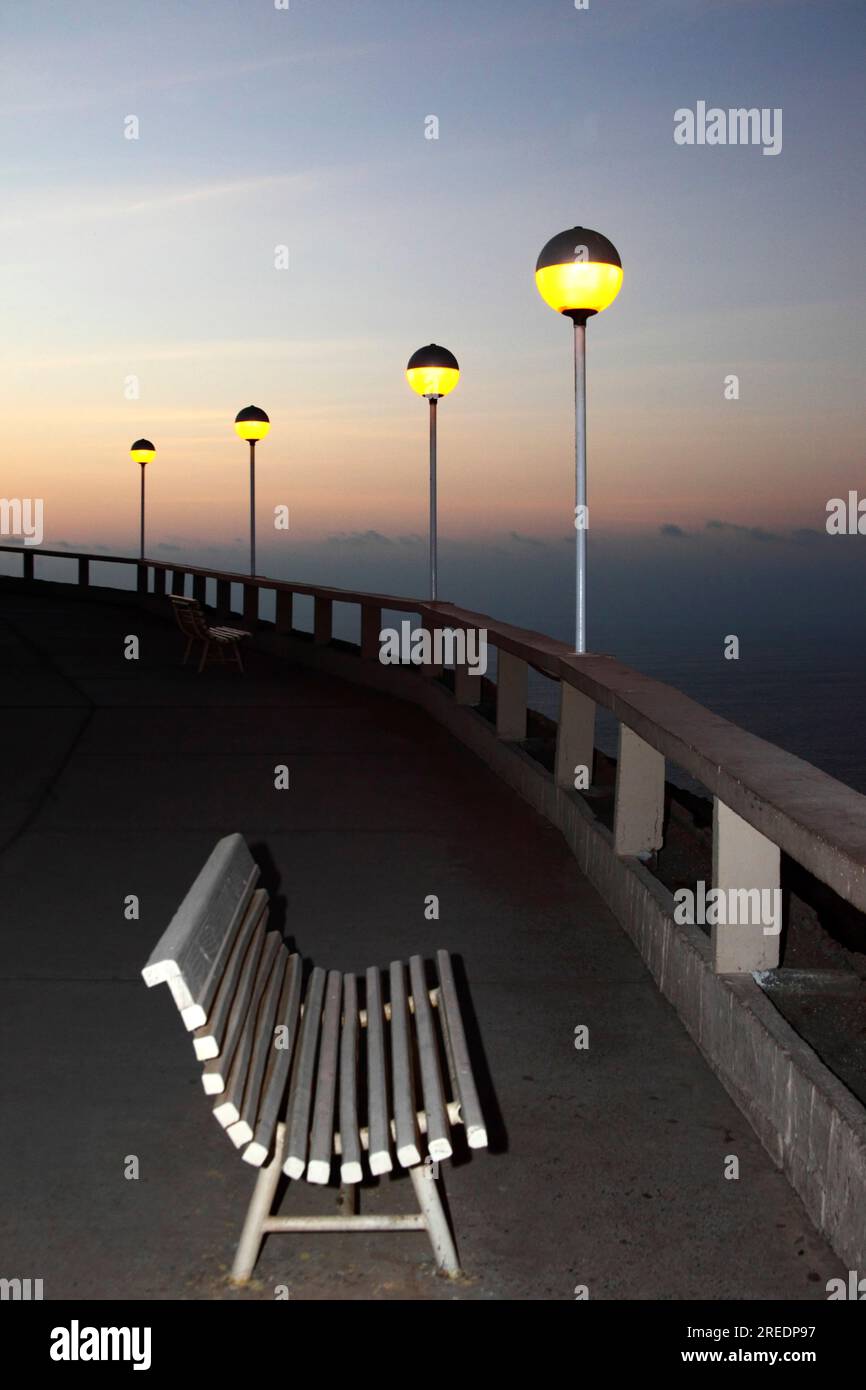 Empty white wooden seat and spherical yellow street lamps on El Morro ...