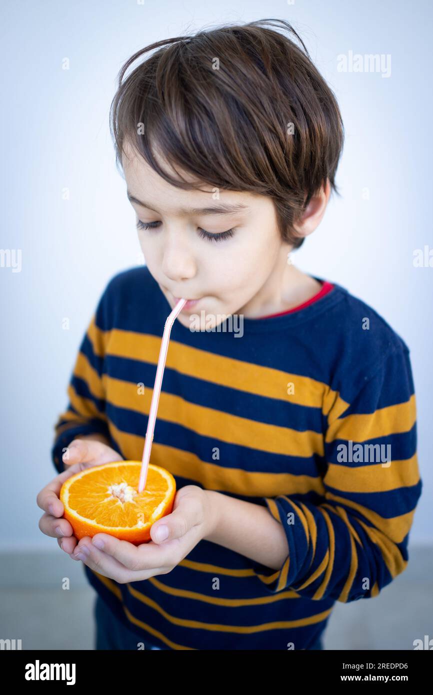 Little cute boy taking juice out of orange Stock Photo - Alamy