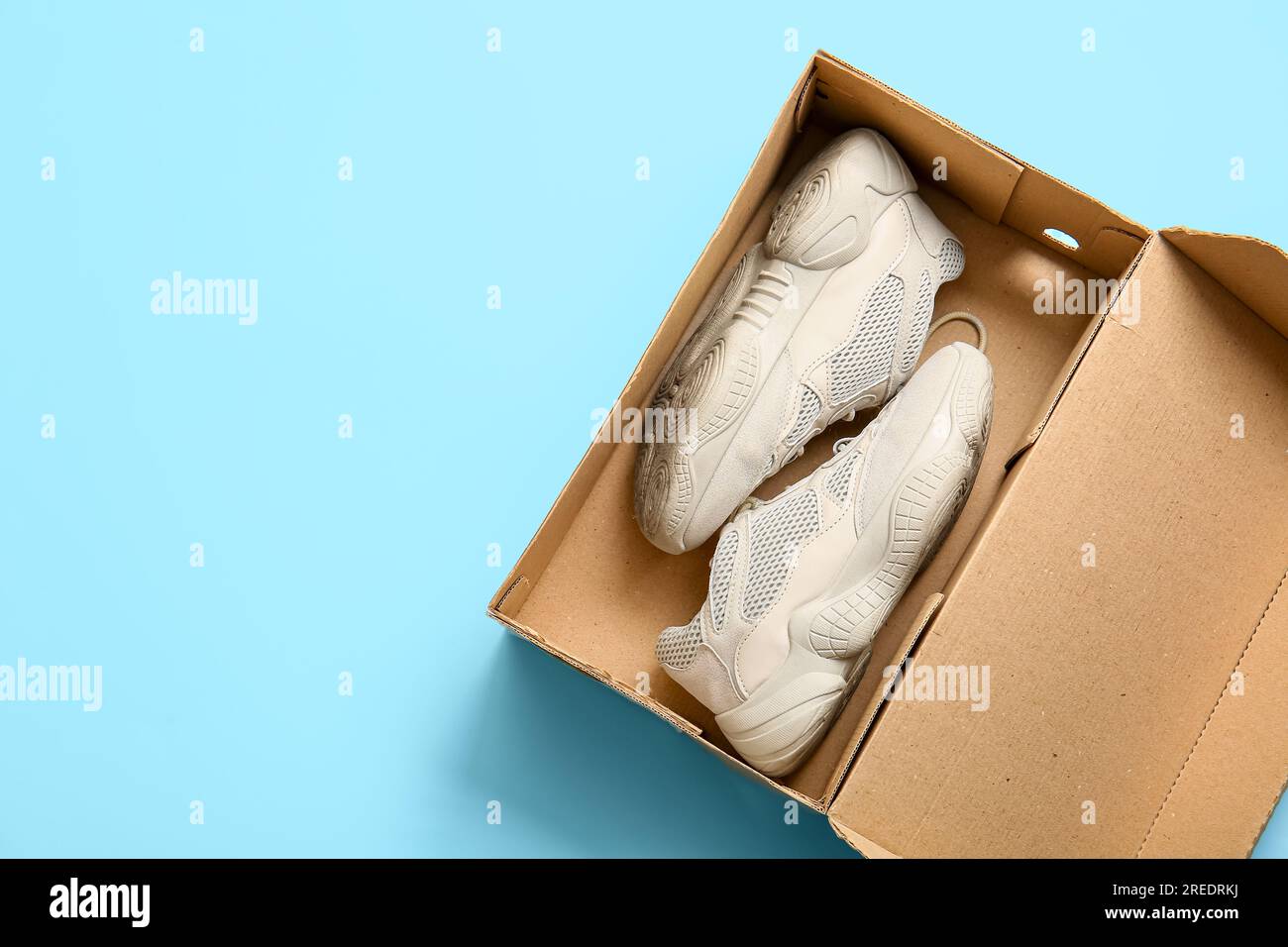 Cardboard box with sports shoes on light blue background Stock Photo ...