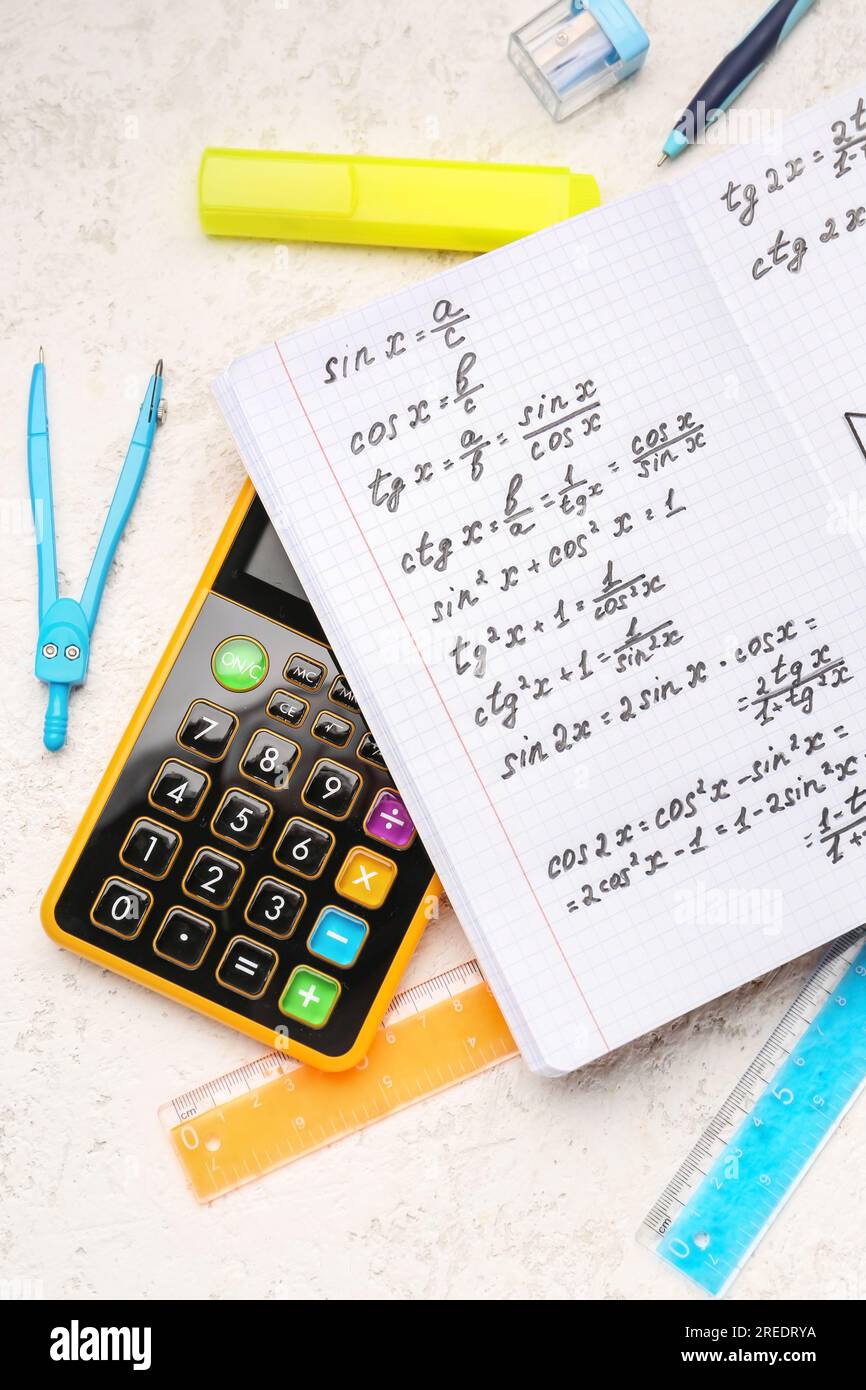 Copybook with maths formulas, calculator and stationery on white grunge ...