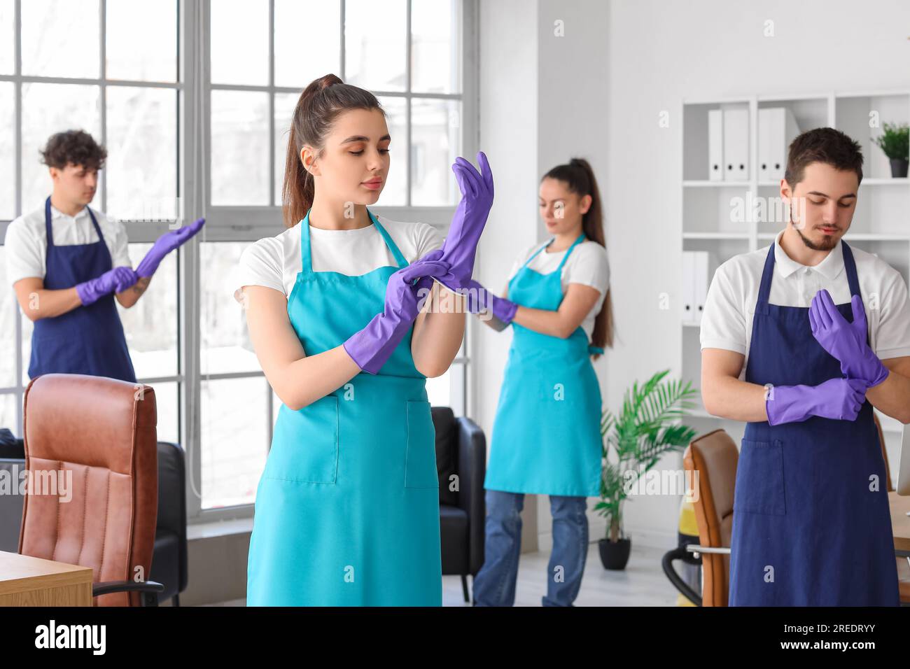 Young janitors putting rubber gloves in office Stock Photo - Alamy