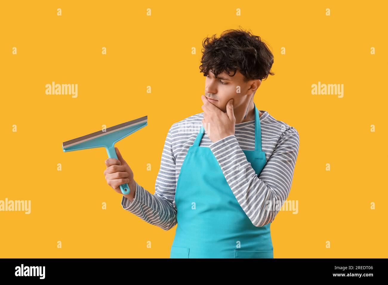 Thoughtful young man with squeegee on yellow background Stock Photo - Alamy