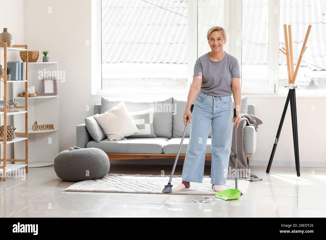 Mature woman sweeping floor in room Stock Photo - Alamy
