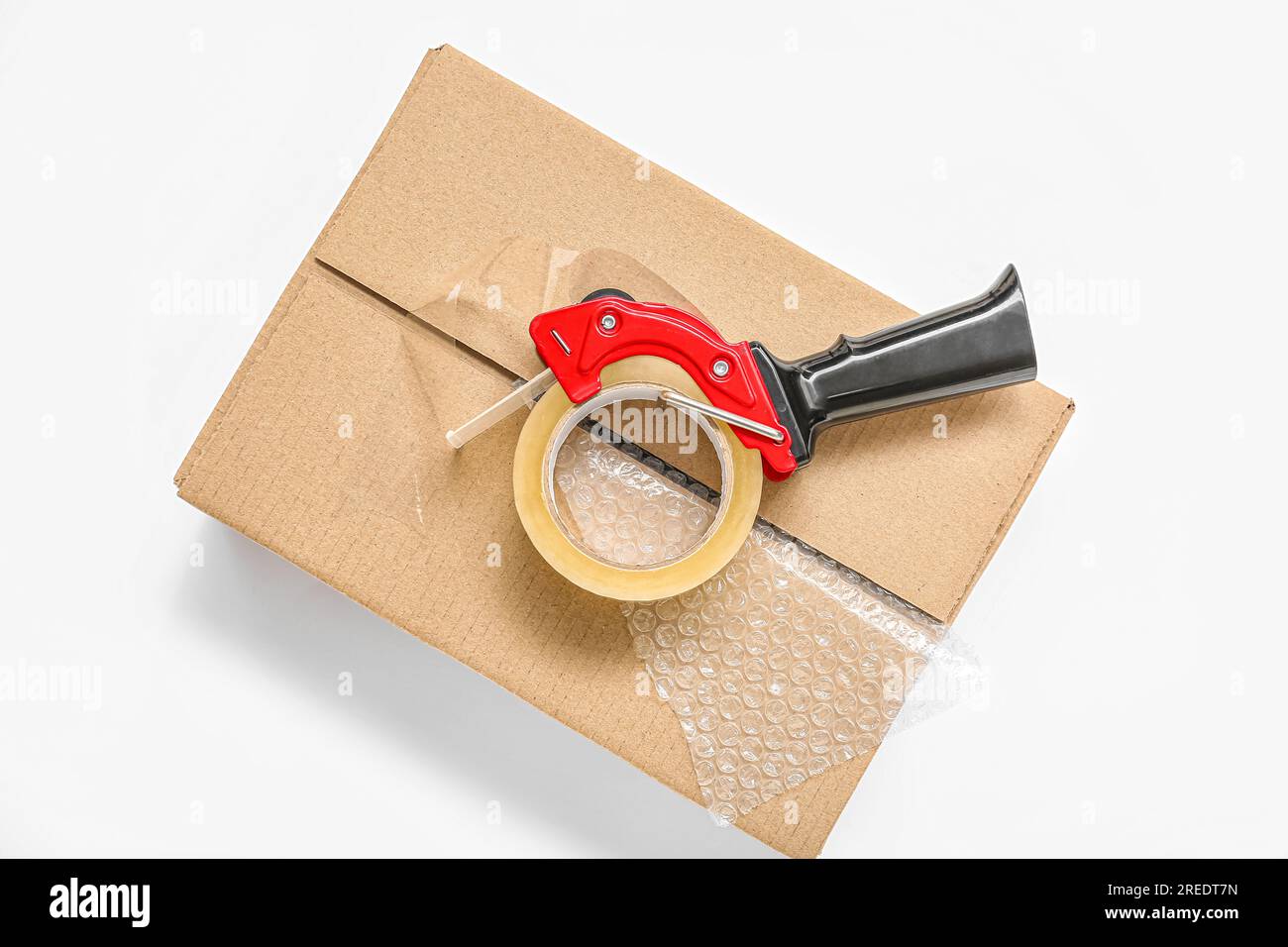 Packing tape dispenser and cardboard box isolated on white background ...