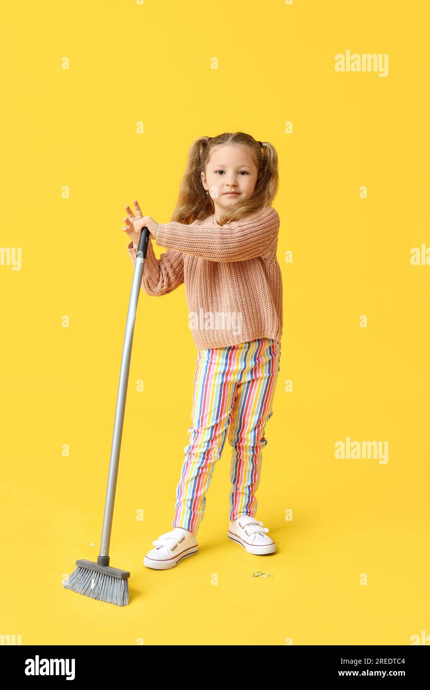Cute little girl with broom on yellow background Stock Photo - Alamy