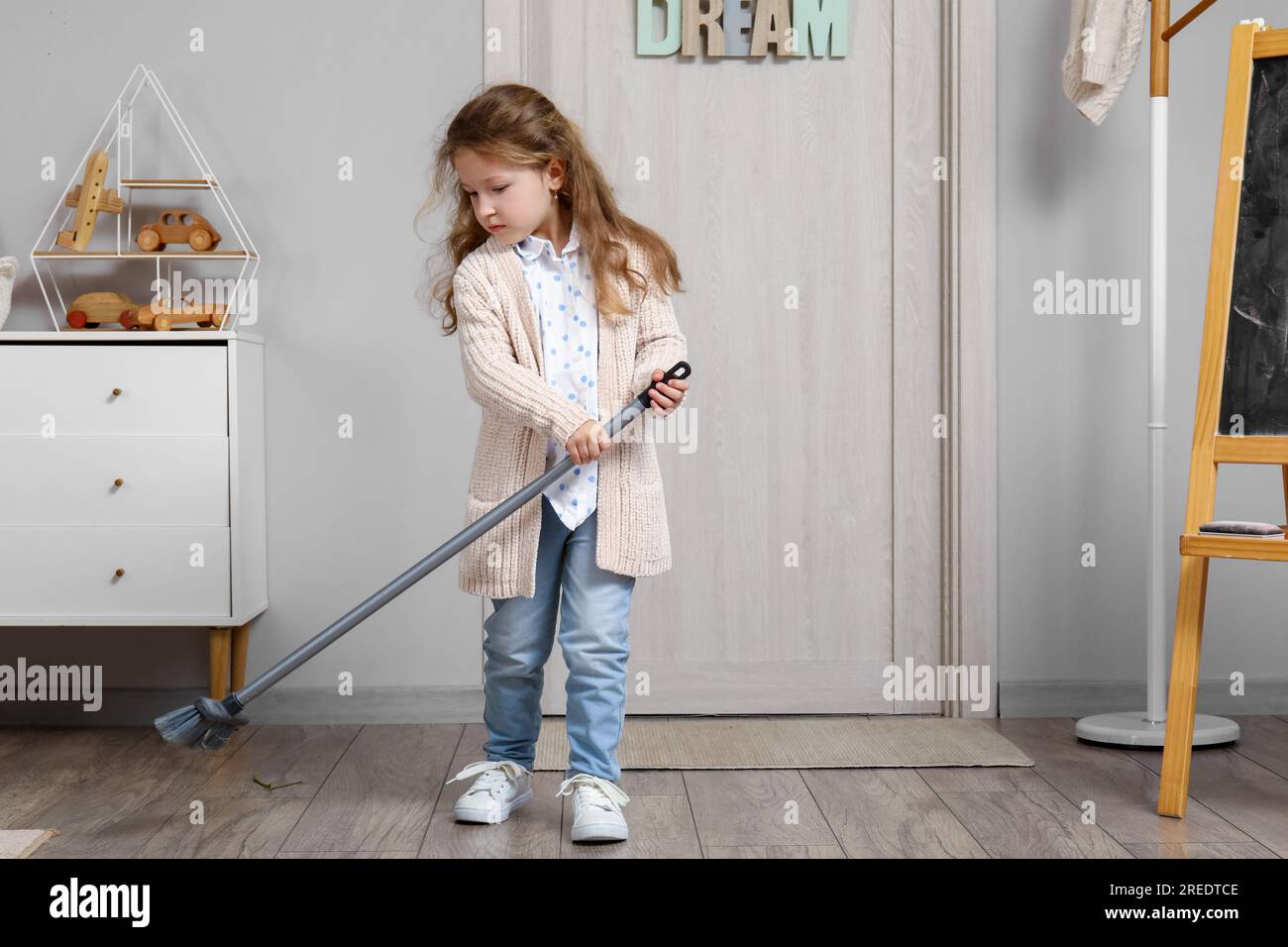 Cute little girl sweeping floor with broom at home Stock Photo - Alamy
