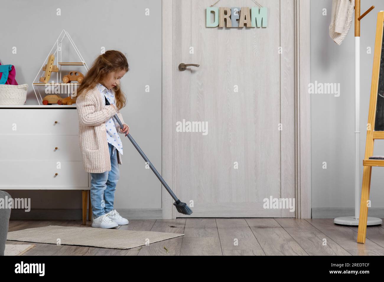 Cute little girl sweeping floor with broom at home Stock Photo - Alamy
