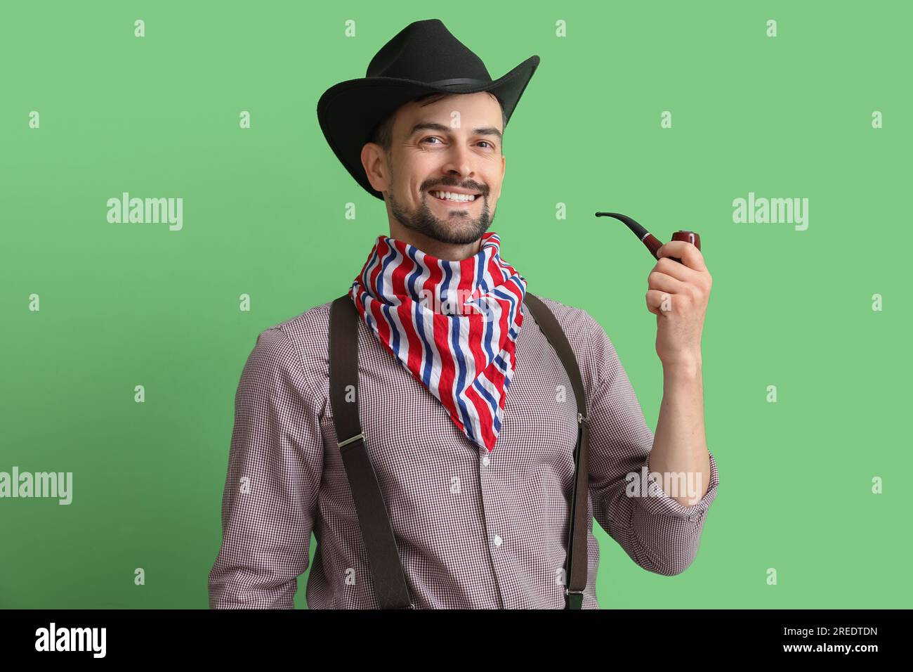 Handsome cowboy with smoking pipe on green background Stock Photo - Alamy