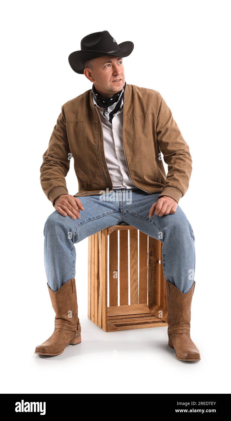 Mature cowboy sitting on white background Stock Photo - Alamy
