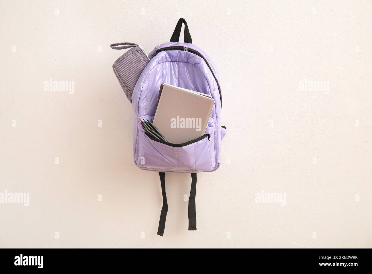 Lilac school backpack with stationery on light background Stock Photo ...