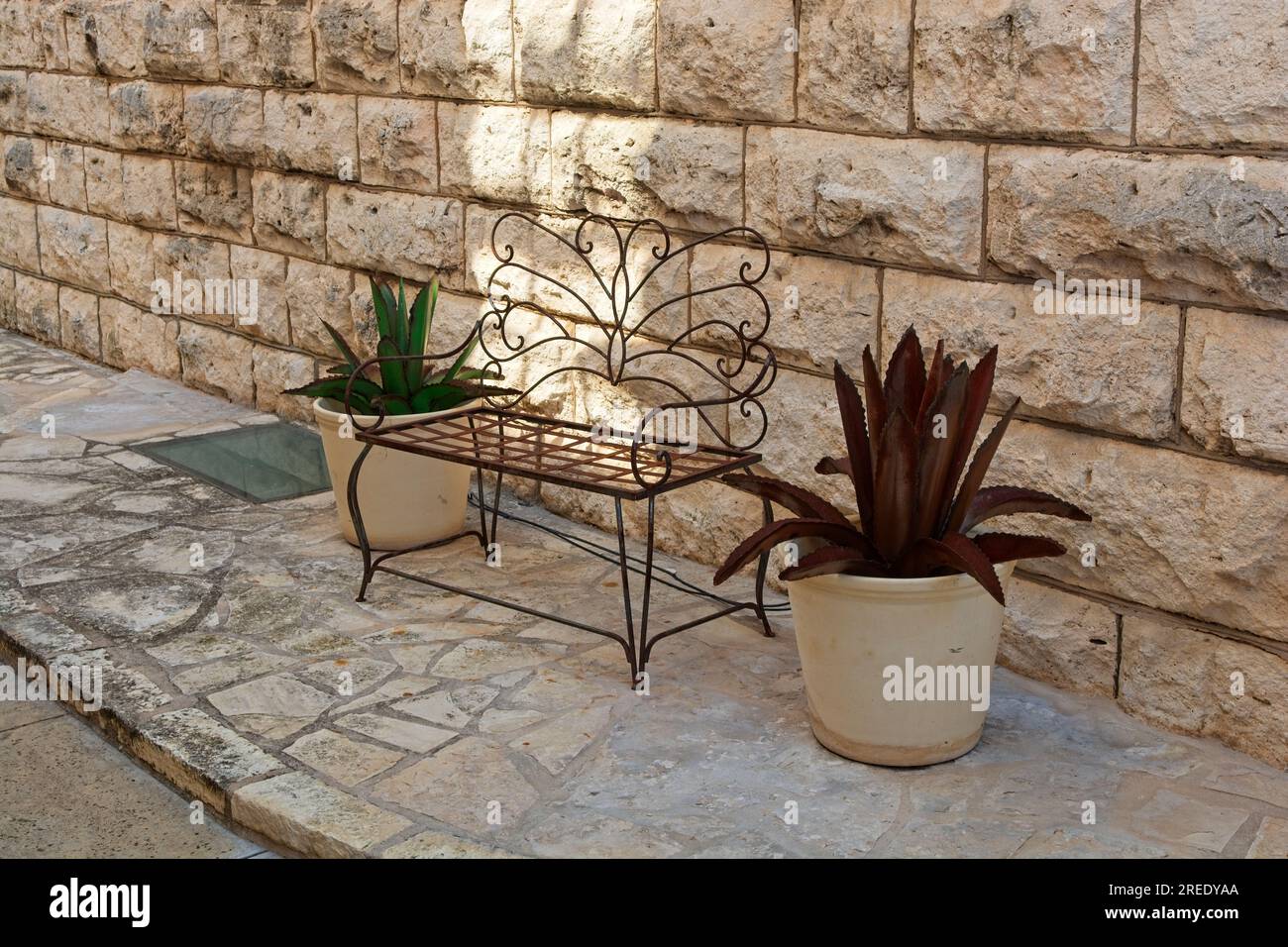 Garden setting in courtyard with planters and wrought iron bench on ...