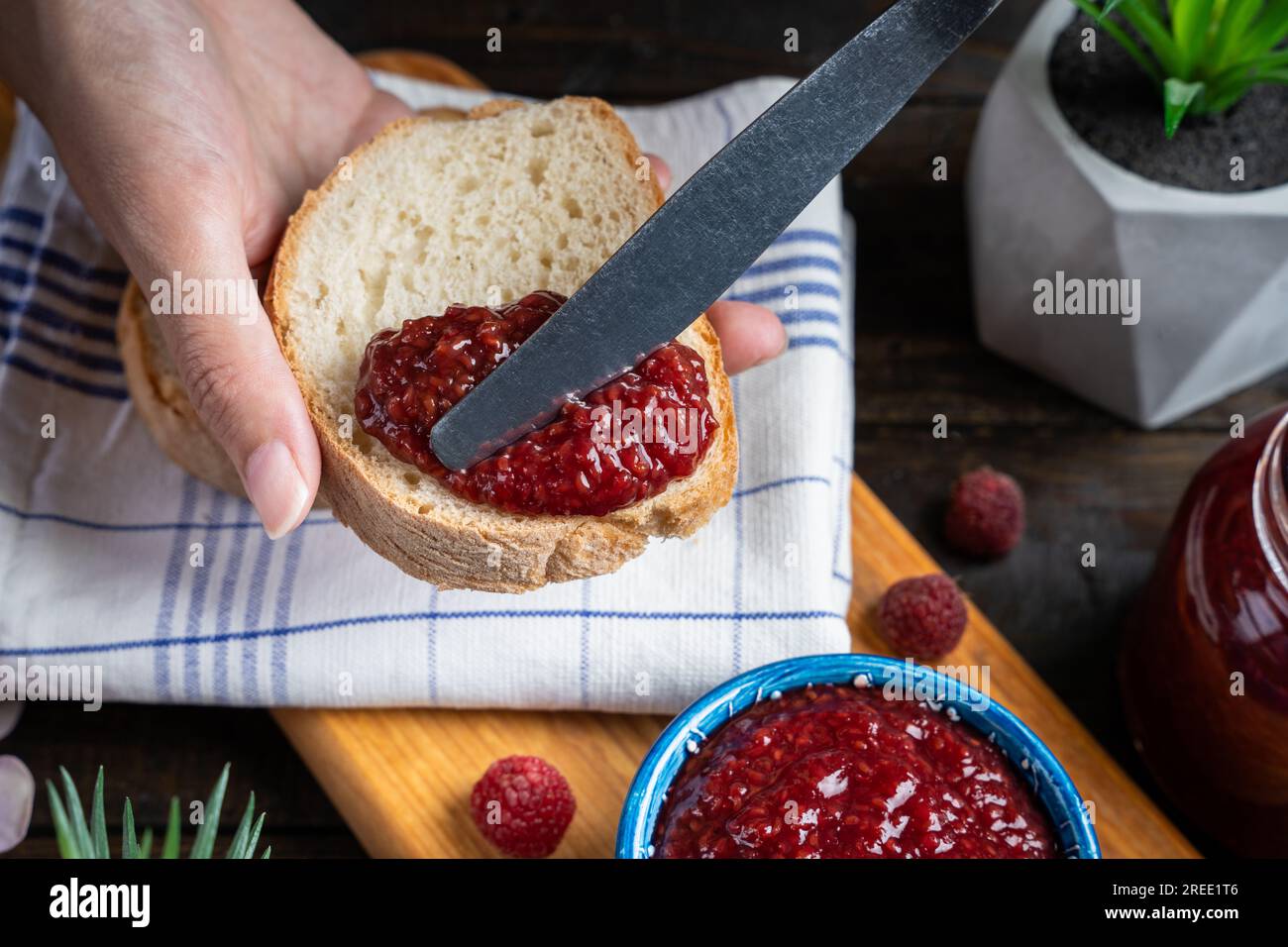 Fresh homemade raspberry jam being spread on a piece of bread with a ...