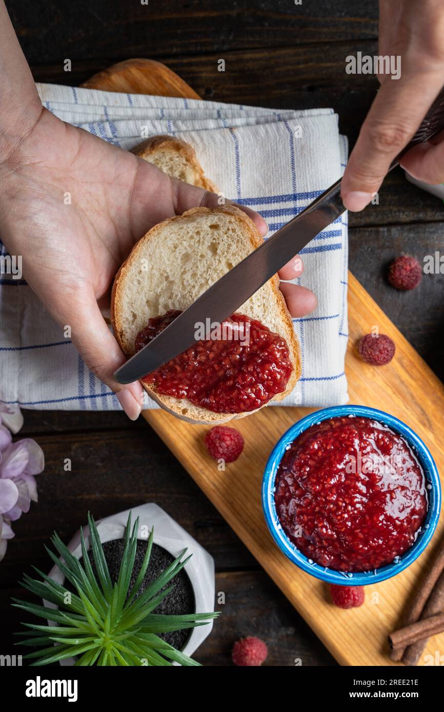 Fresh homemade raspberry jam being spread on a piece of bread with a ...