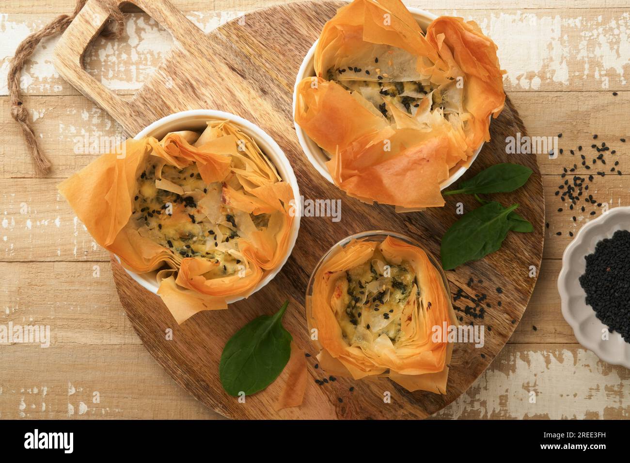 Filo pies with soft feta cheese and spinach in ceramic molds on old ...