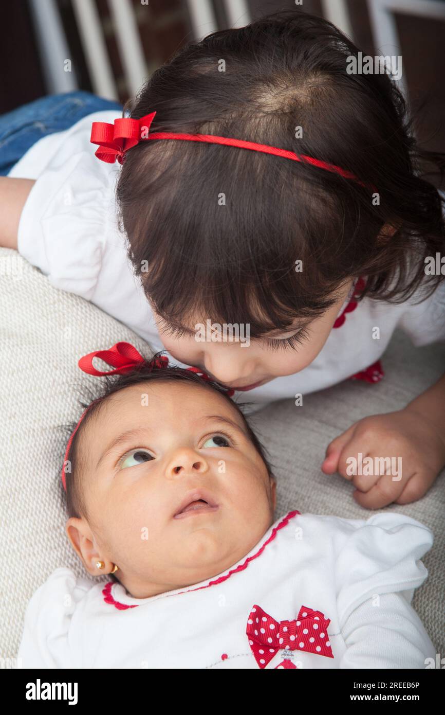 One month old baby girl at home with her big sister. Love between ...