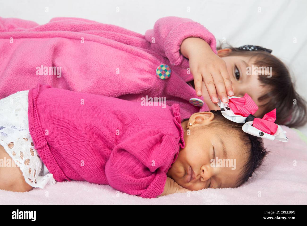 One month old baby girl at home with her big sister. Love between ...