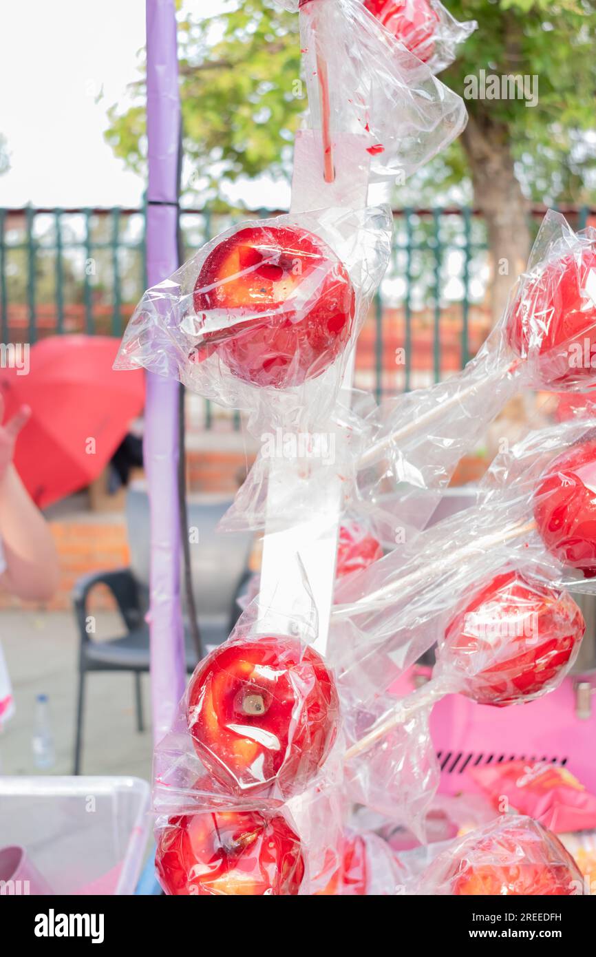Red candy apples wrapped in plastic at a street food stand at a street ...
