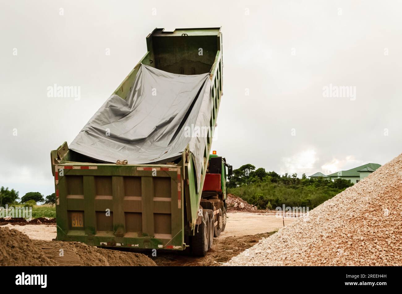 The tailgate of a green tipper body truck is left suspended on the two ...