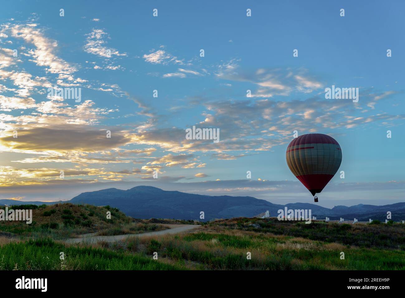 Hot air balloon taking off from the ground at dawn on a blue sky day ...