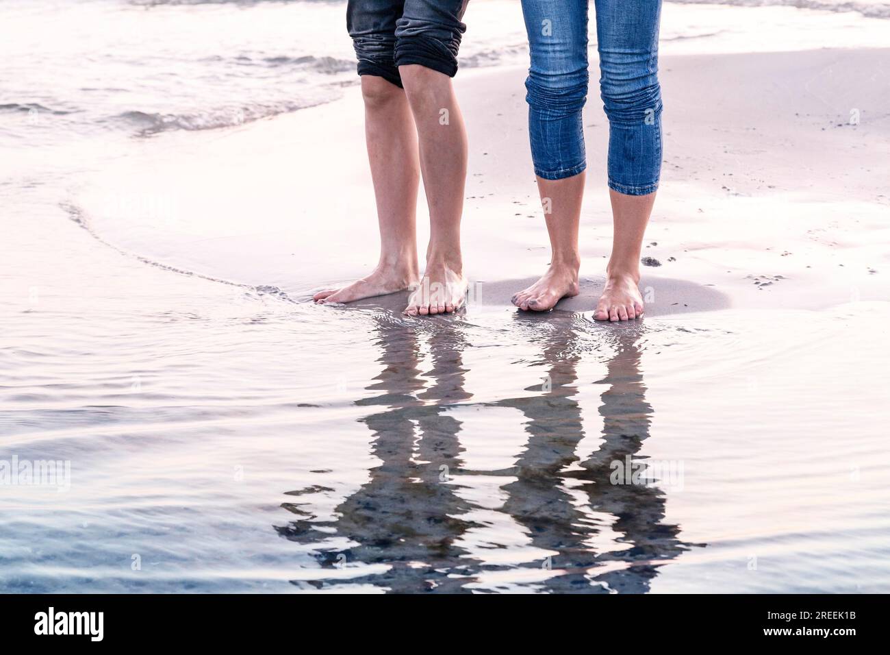 The legs of tow people reflected in the ocean Stock Photo - Alamy