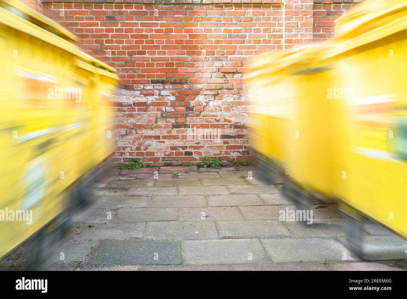 Moving yellow dumpster in front of a red brick wall Stock Photo - Alamy