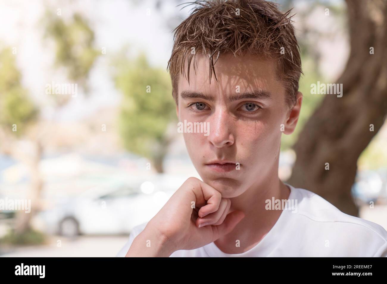 Portrait of a young man with his fist on his chin Stock Photo - Alamy