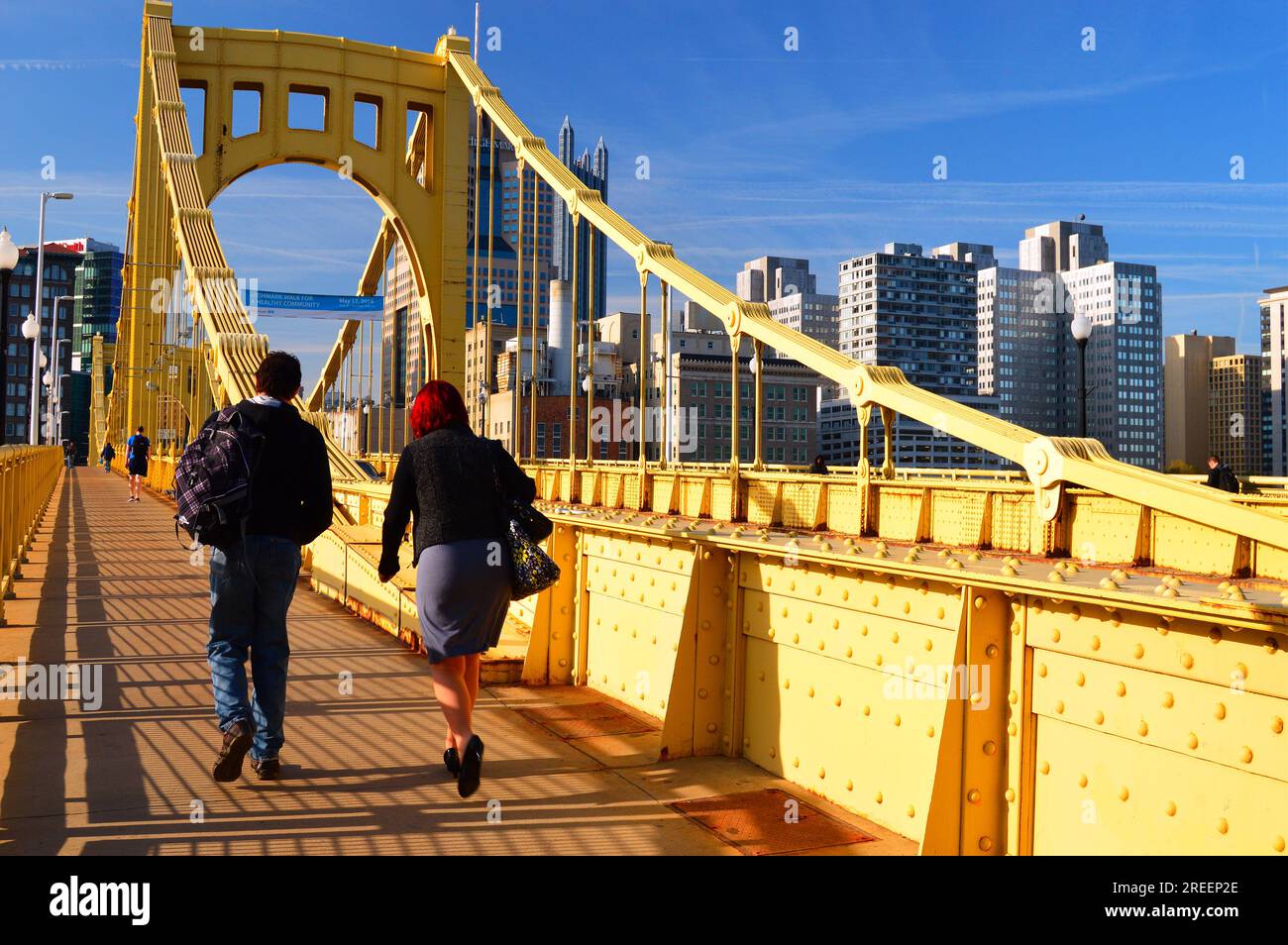 A couple walks across the Roberto Clemente Bridge, heading towards ...
