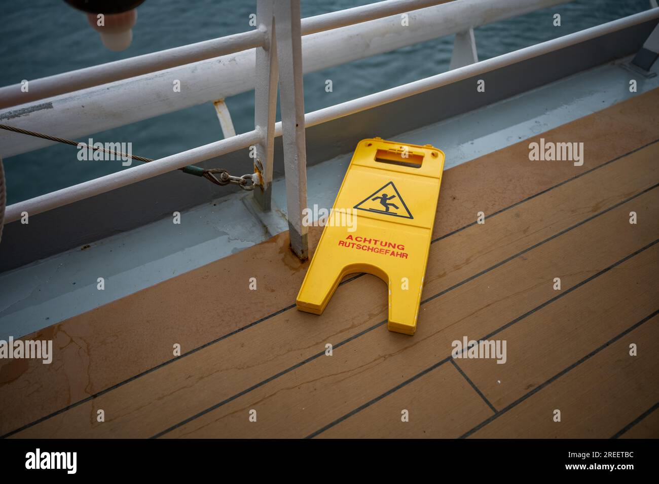 Yellow caution danger of slipping sign lying down on a wet floor of a ...