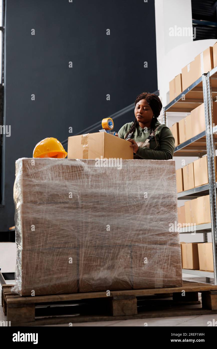 African american manager using adhesive tape to pack customers orders ...