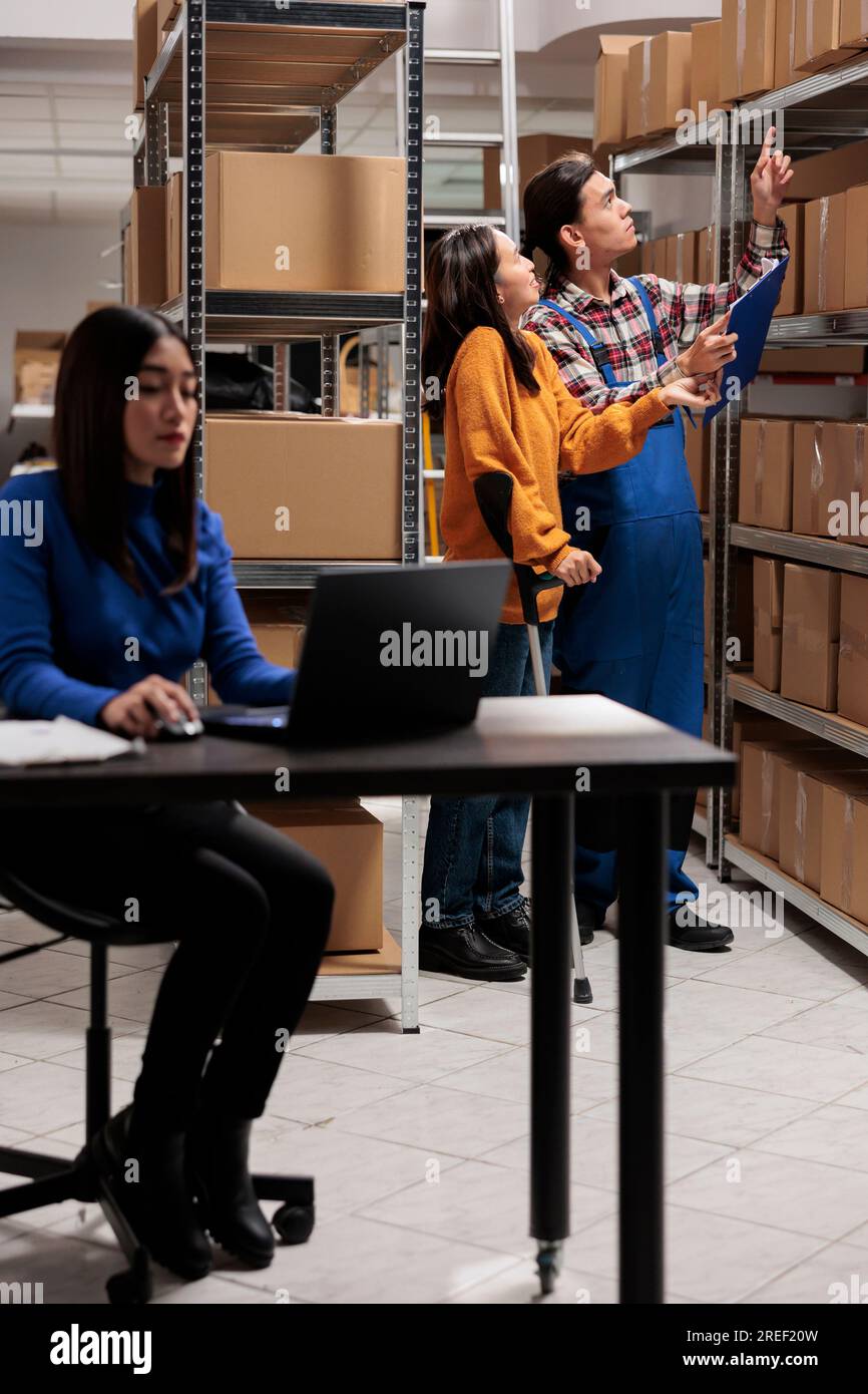 Warehouse asian man and woman managers picking order and taking parcel ...