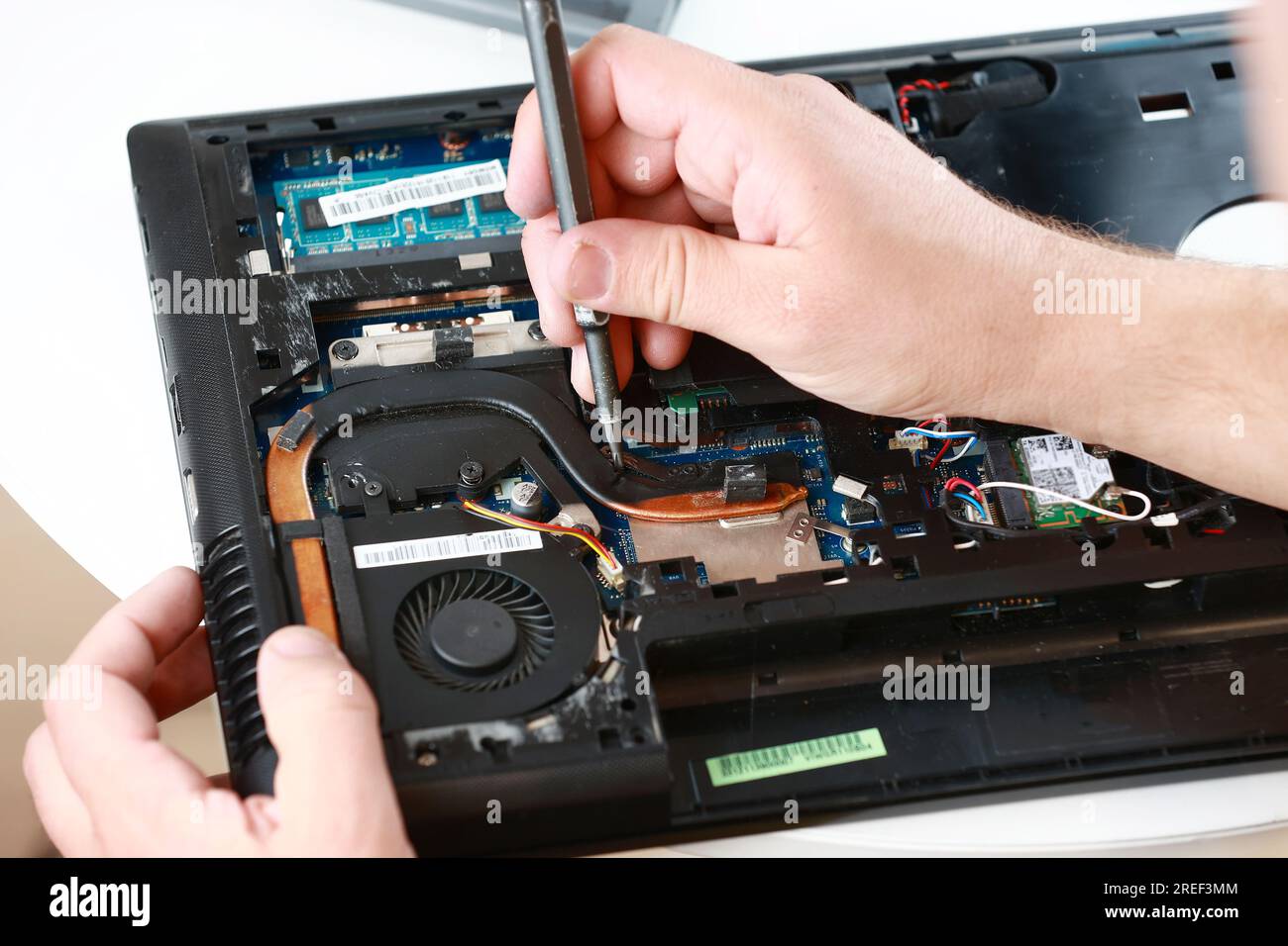 Repaiman with screwdriver fixing disassembled laptop parts. Technical ...