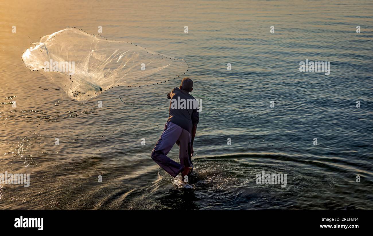 A fishermen throwing fishing net during sunrise in Al Khobar seaside ...