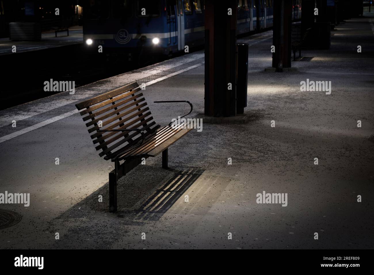 An empty bench on a train platform at night, waiting for the elusive ...
