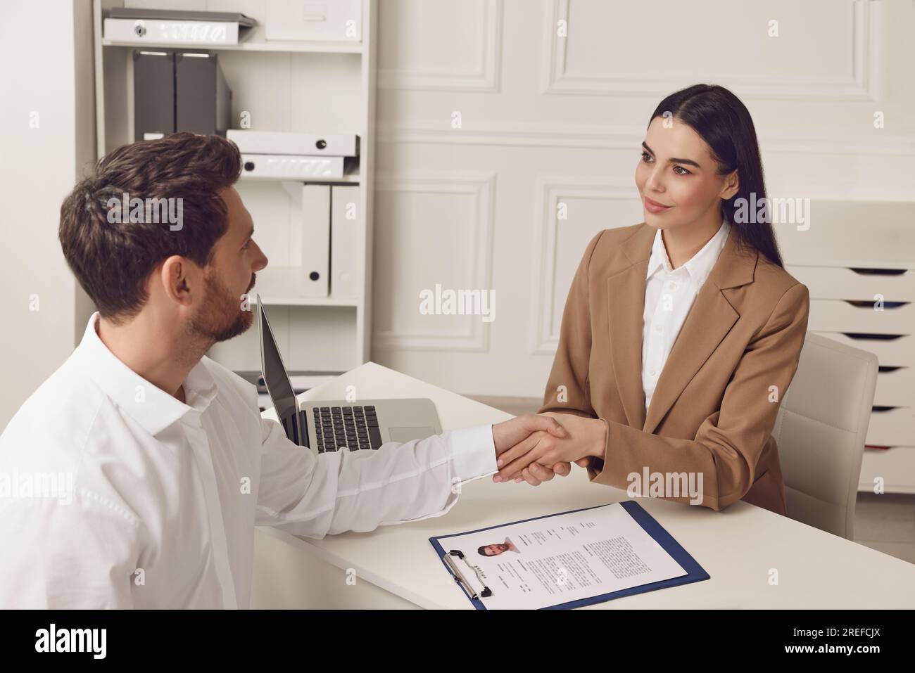 Human resources manager shaking hands with applicant during job interview in office Stock Photo ...