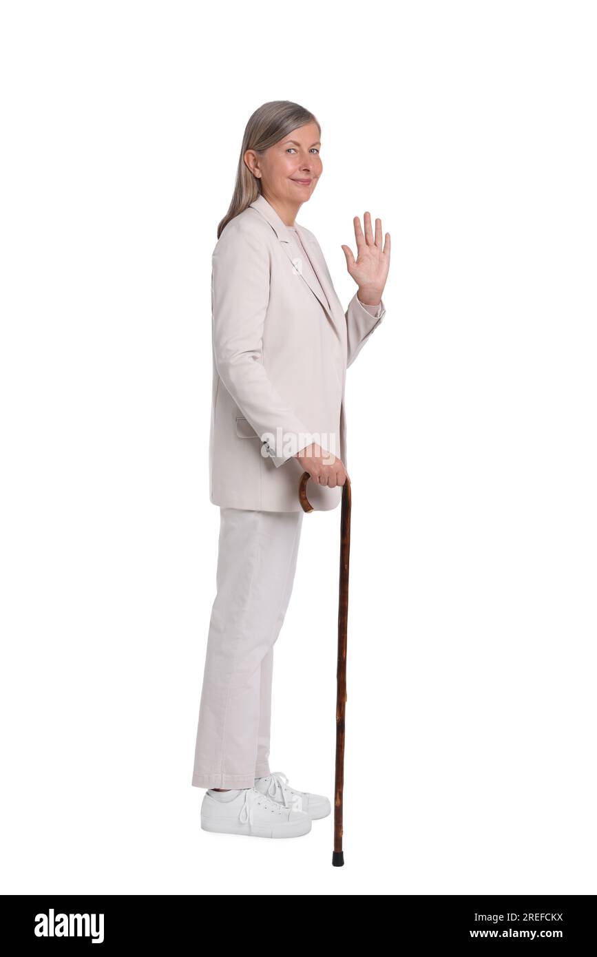 Senior woman with walking cane waving on white background Stock Photo ...
