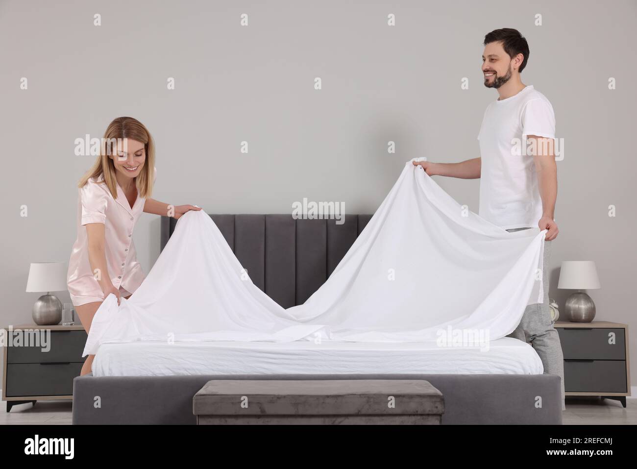 Couple changing bed linens in room. Domestic chores Stock Photo - Alamy