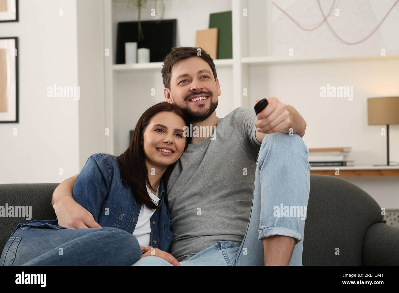 Happy couple watching show at home. Man changing TV channels with ...