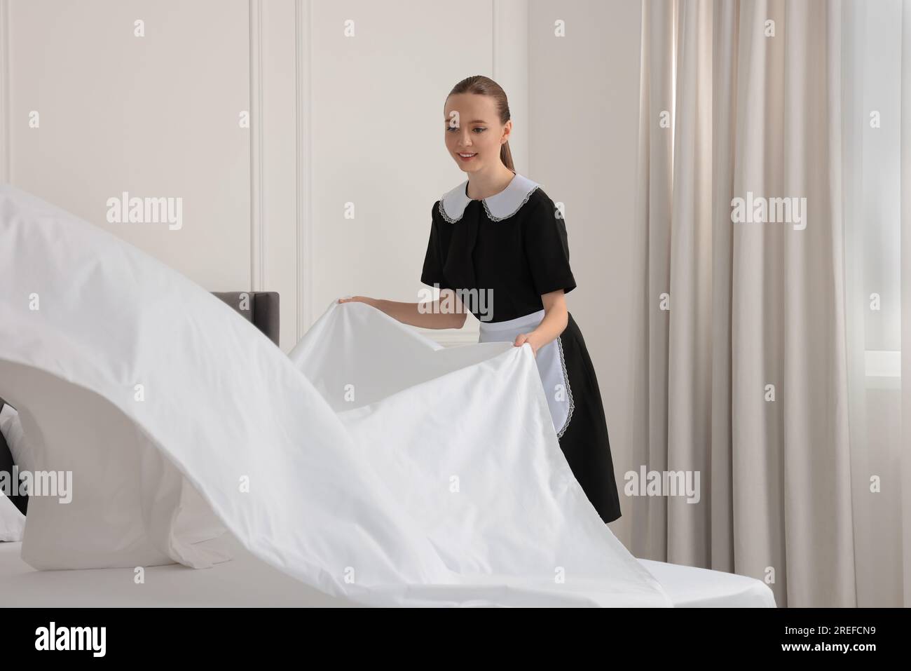 Young maid making bed in hotel room Stock Photo - Alamy