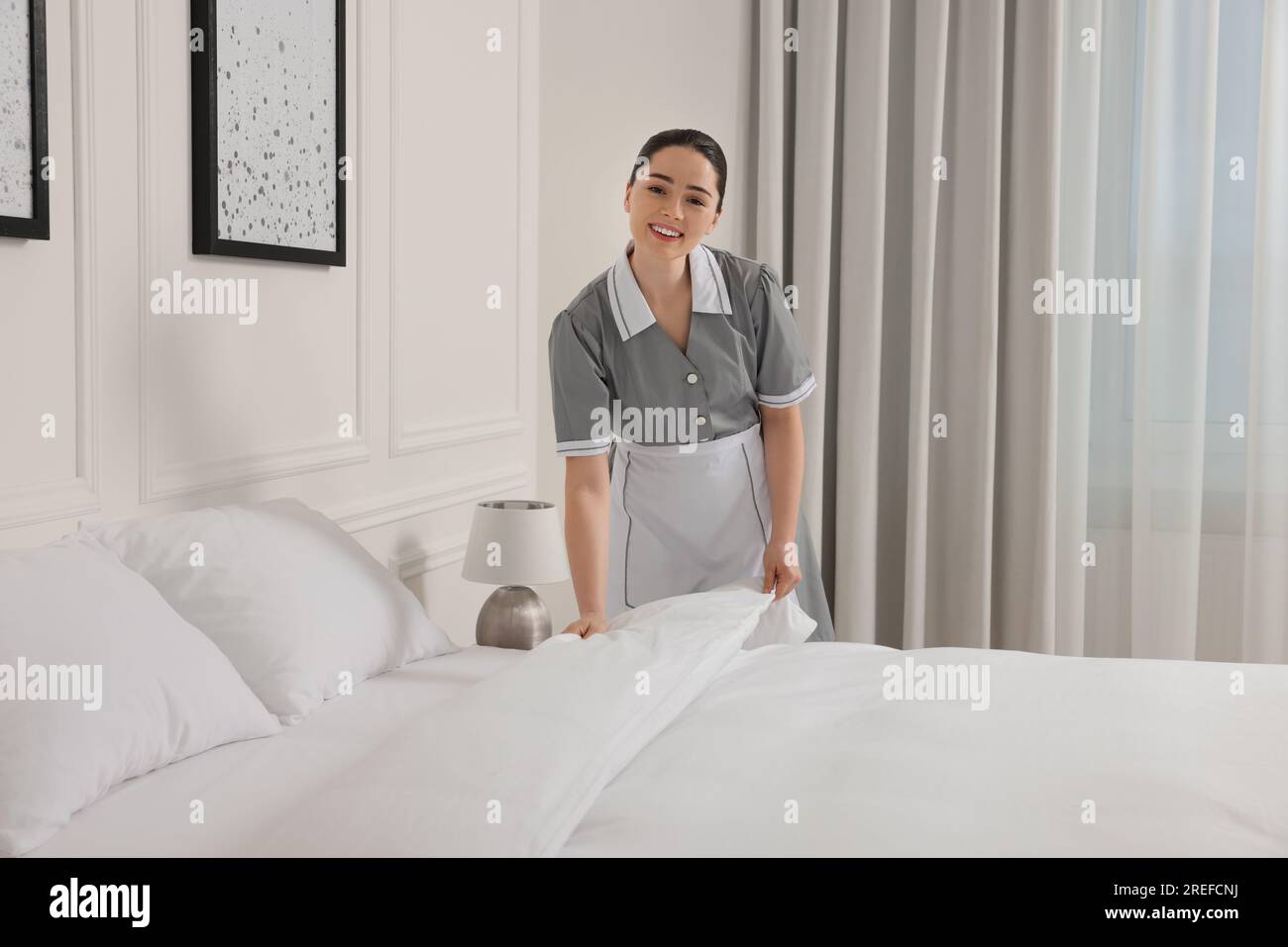 Young maid making bed in hotel room Stock Photo - Alamy