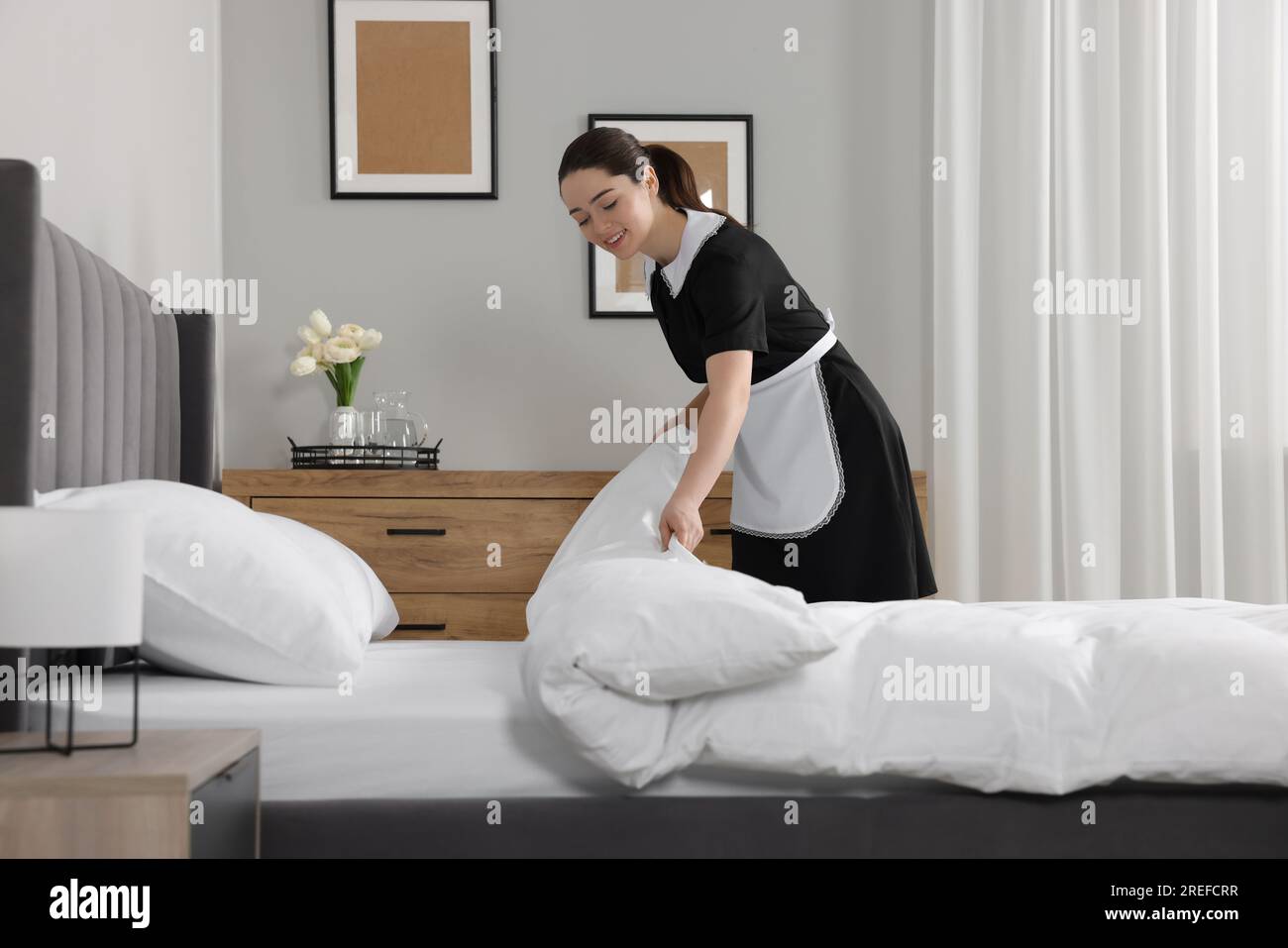 Young chambermaid making bed in hotel room Stock Photo - Alamy