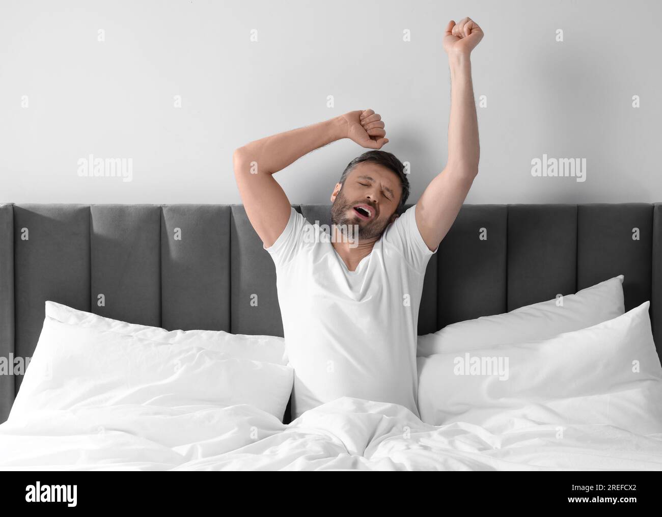 Sleepy man stretching in soft bed at home in morning Stock Photo - Alamy