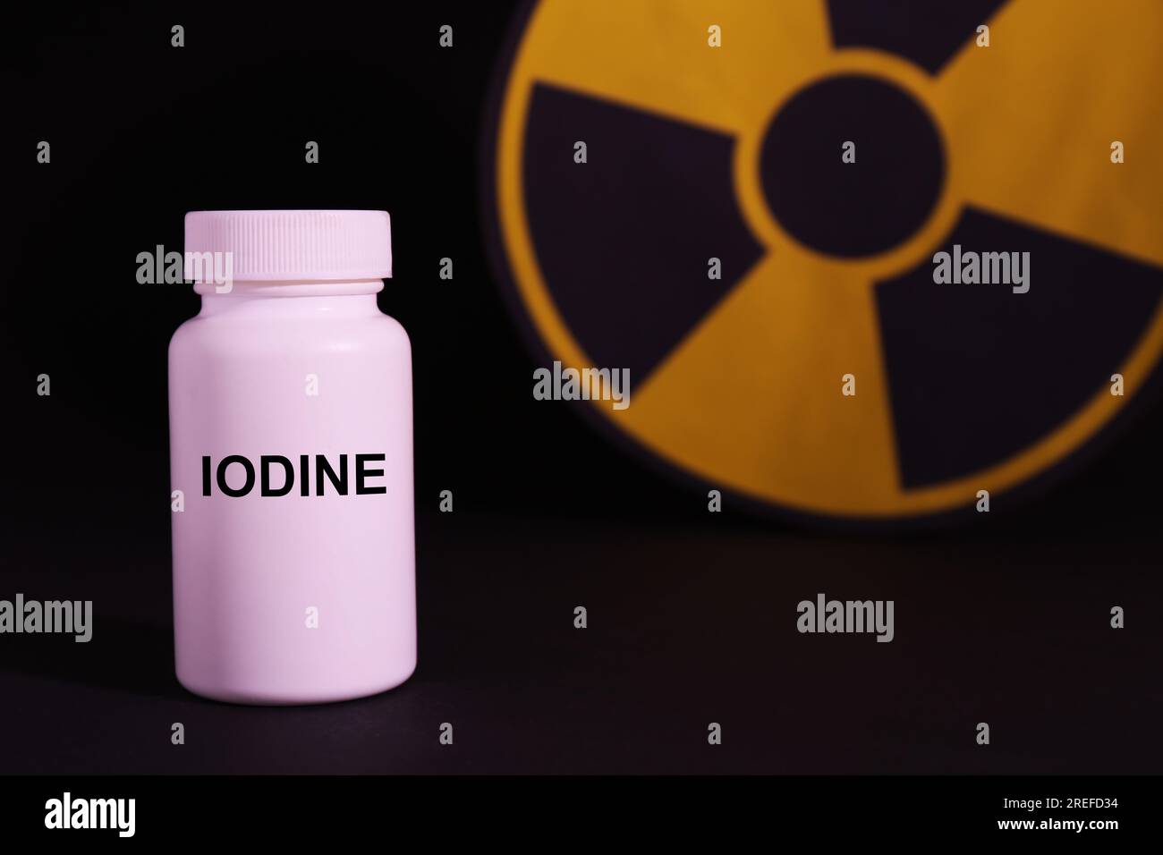 Plastic container of medical iodine and radiation sign on black ...