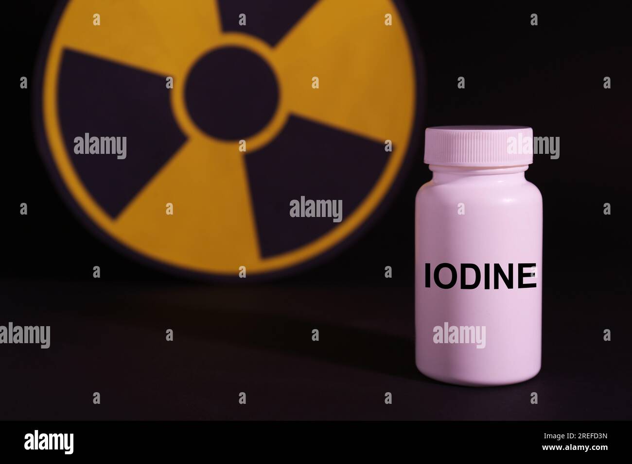 Plastic container of medical iodine and radiation sign on black ...